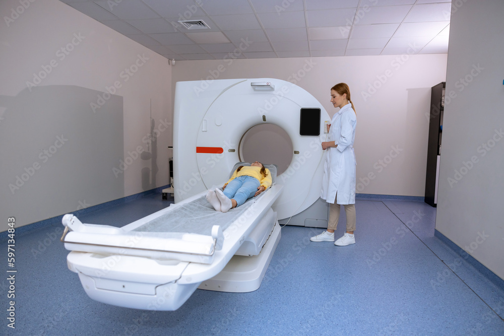 Little girl lying on table of mri scan machine female radiographer ...