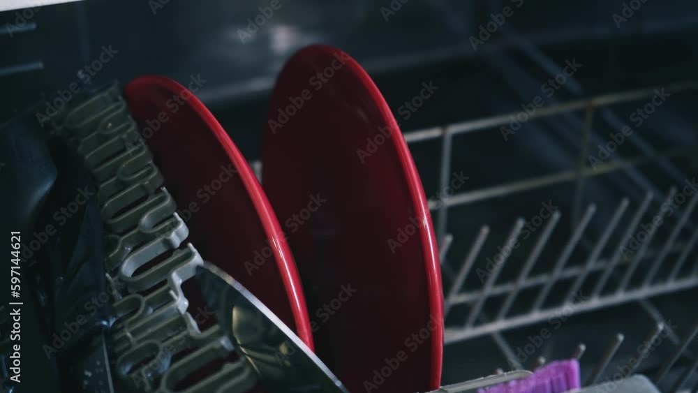 Loading dirty plates, crockery and glass into the dishwasher. Puts ...