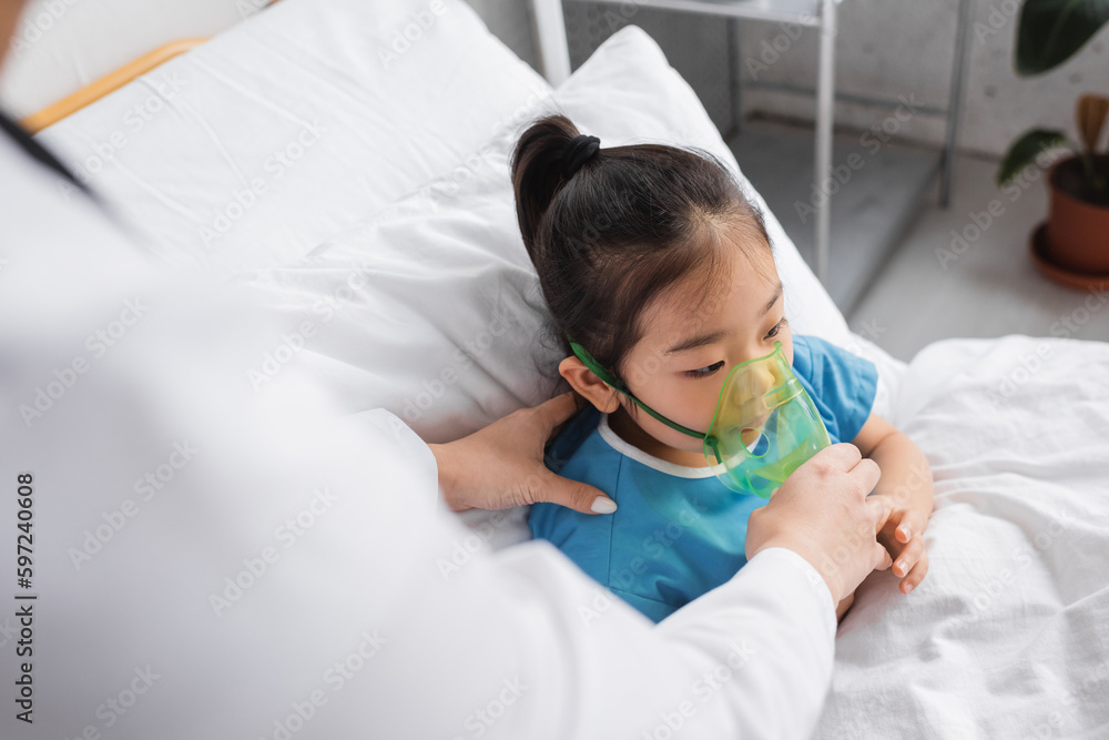 Poster blurred doctor adjusting oxygen mask on sick asian child on ...