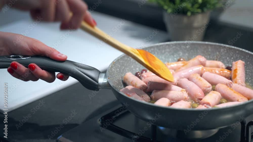 Woman cooking on trendy gas stove in the kitchen, chef frying cut ...