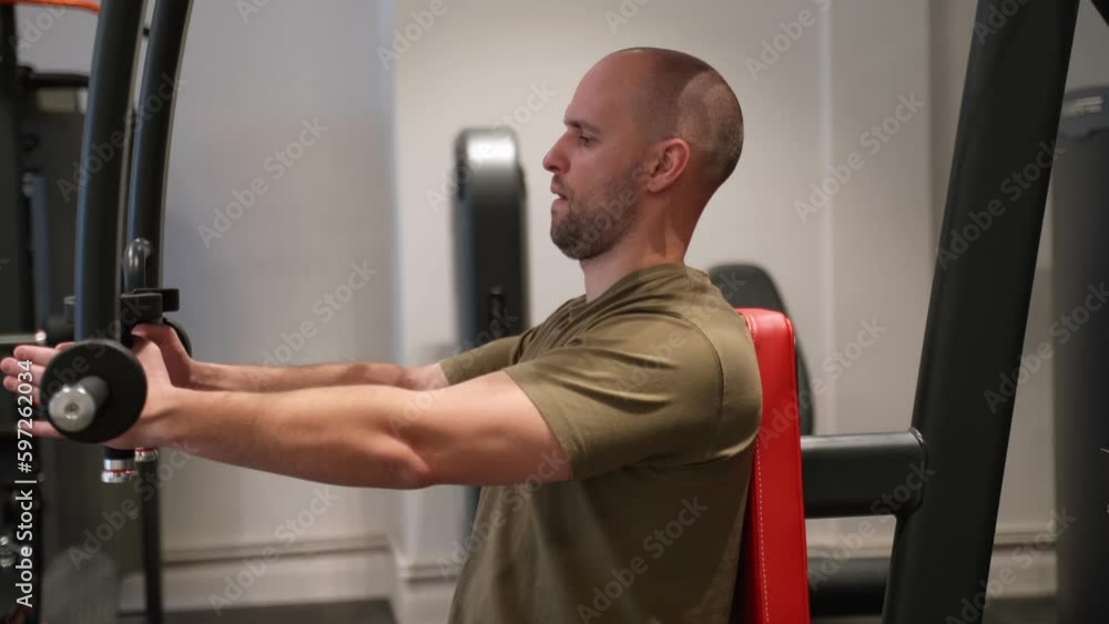 Athlete bodybuilder pumping muscles in the gym, flattens the chest ...