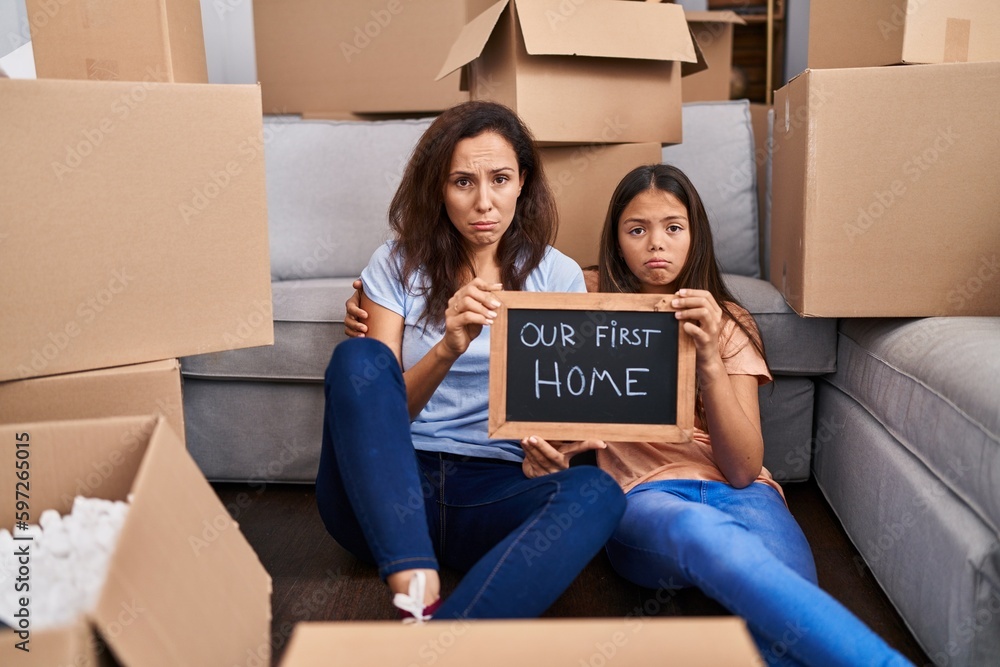 Young mother and daughter sitting on the floor at new home depressed ...