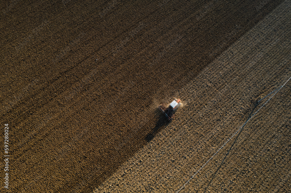 Foto de farmer driving a crawler tractor ploughing and power harrowing ...