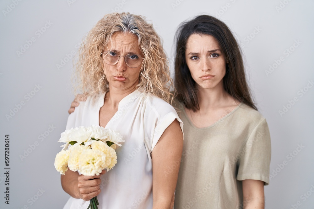 Mother and daughter holding bouquet of white flowers depressed and ...