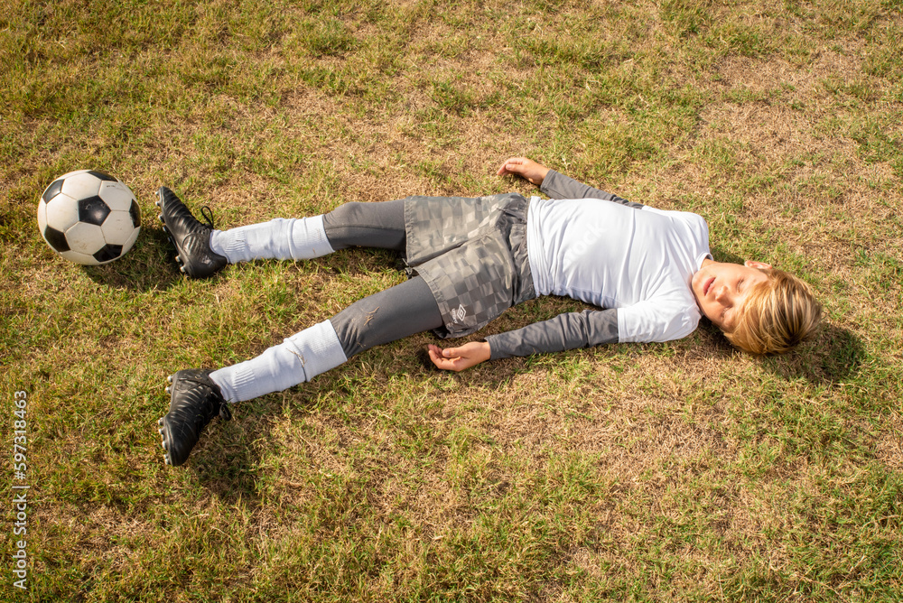 Young boy soccer player lying unconscious injured on the soccer field ...