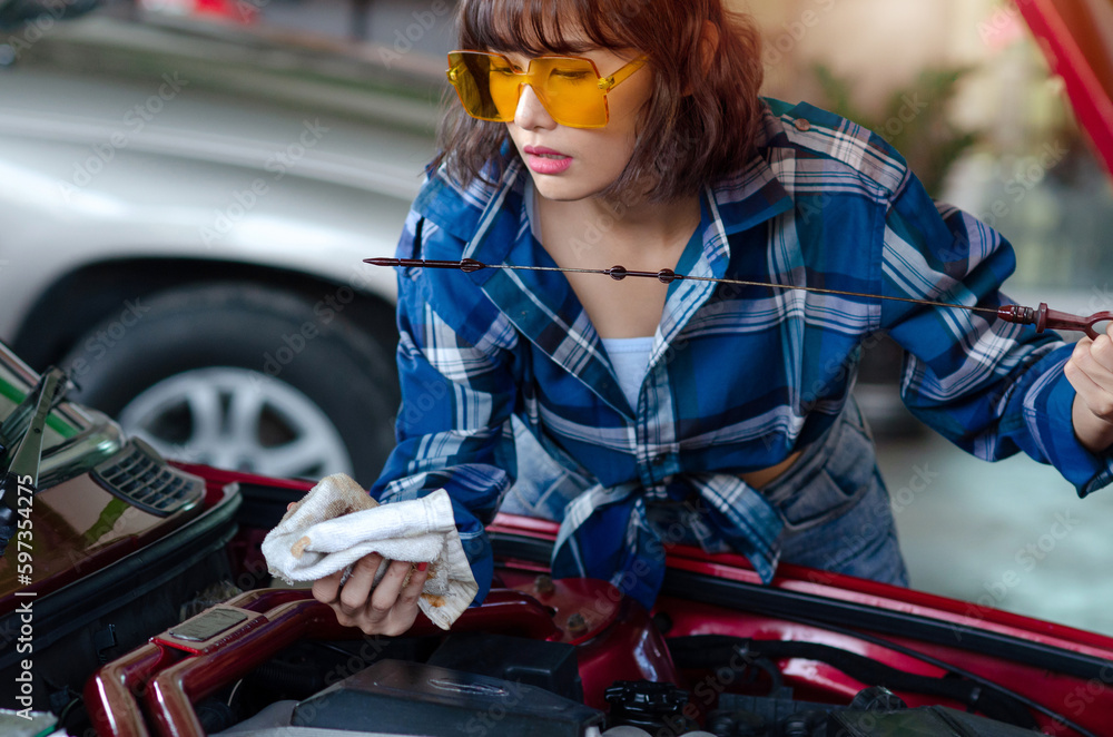 Asian female mechanic working at the repair garage, check engine oil ...