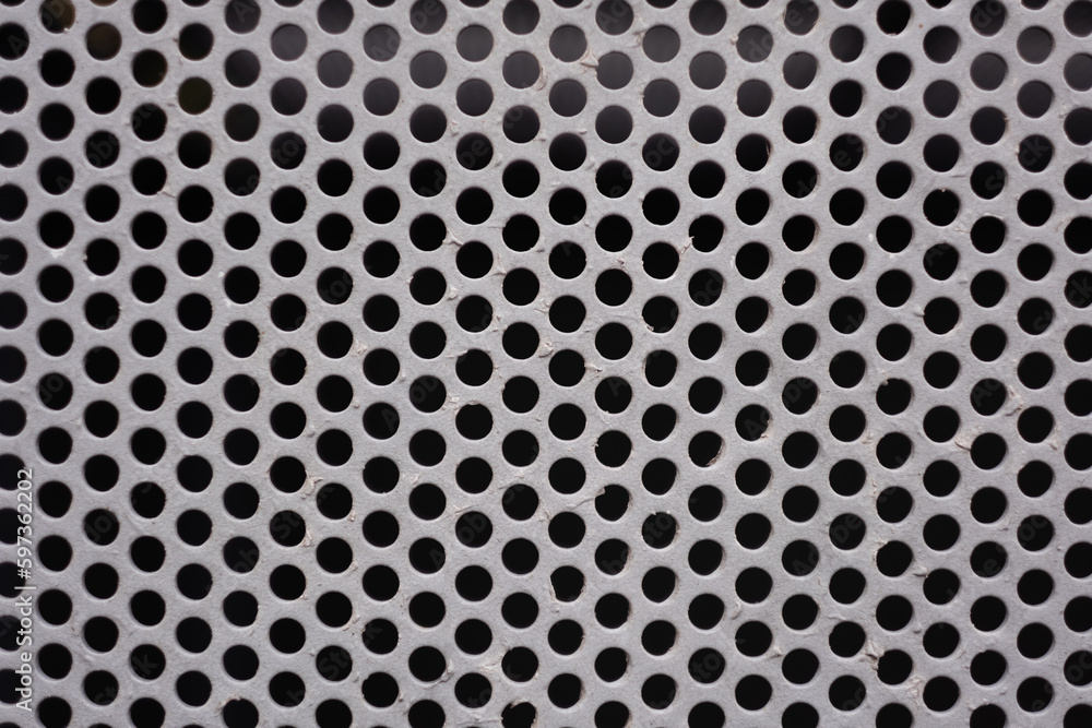 A steel panel has a dizzying pattern of laser-cut holes arranged in a ...