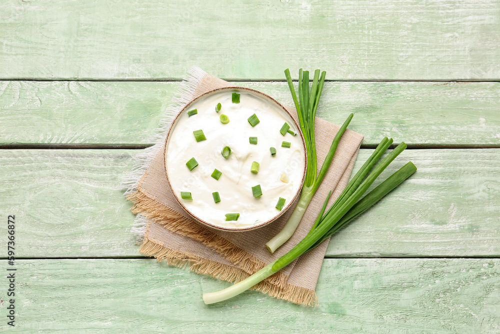 Bowl of delicious sour cream with green onion on light wooden ...