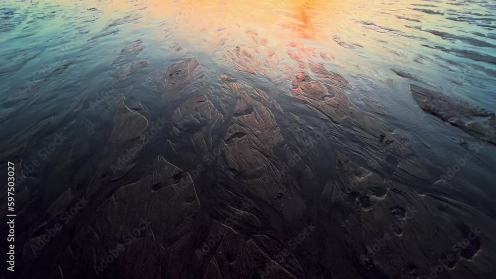 Beautiful static background with wet black sand reflecting sunset sky ...