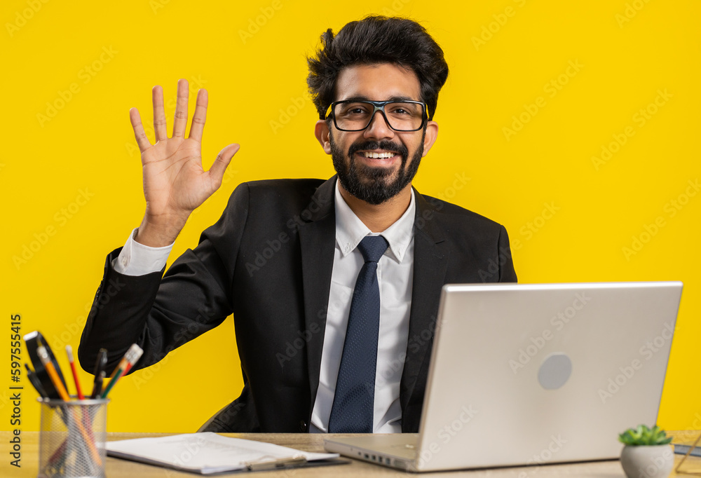 Indian business man working on laptop smiling friendly at camera ...