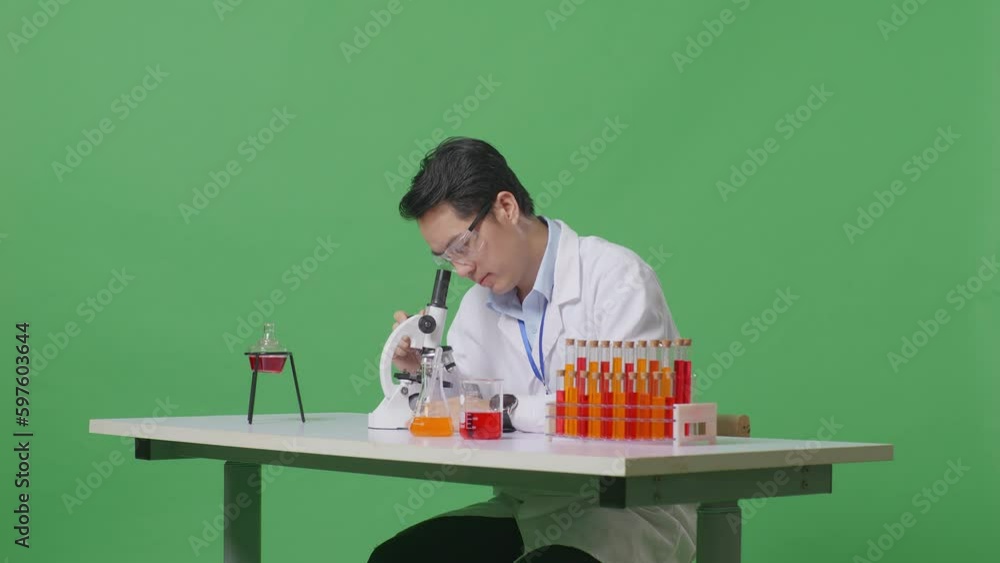 Side View Of Asian Man Scientist Looking Through A Microscope On The ...