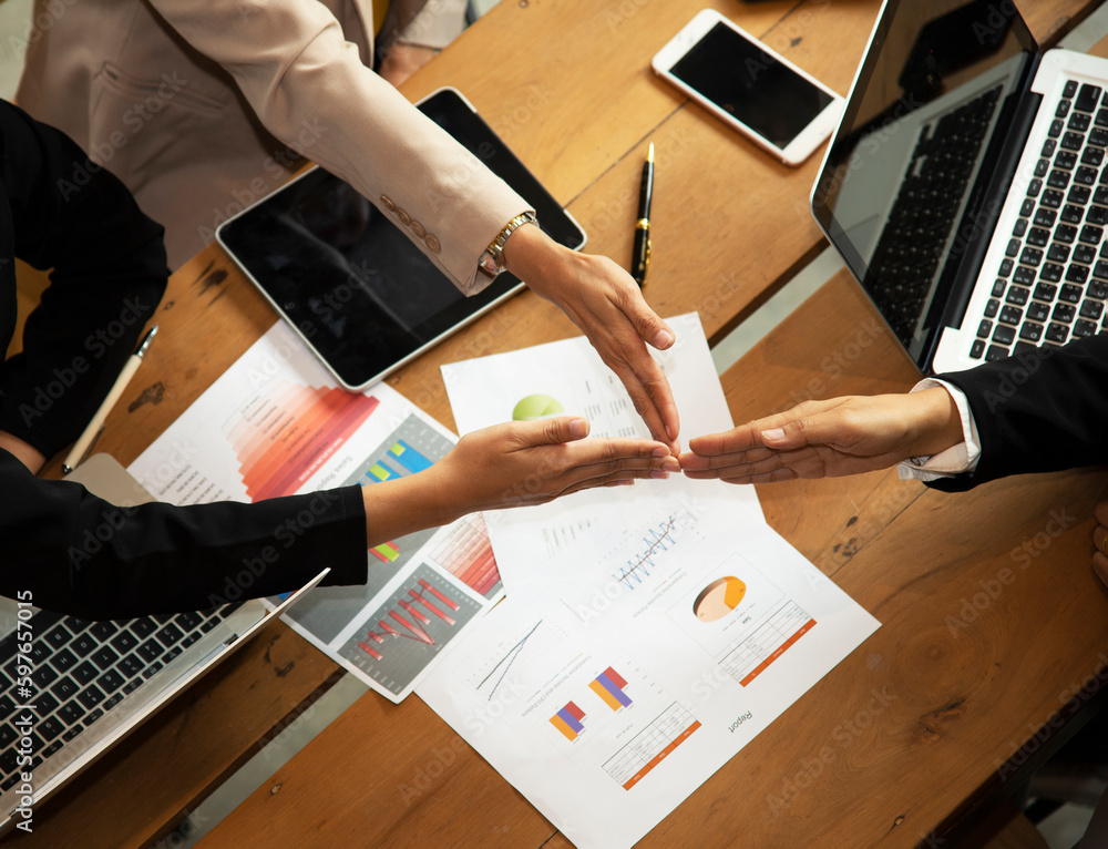 Asian business team putting their hands together on top of each other ...