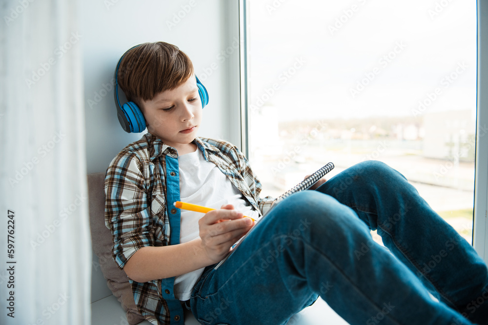 Dreamy happy teen boy writing on notepad at home distance thinking ...