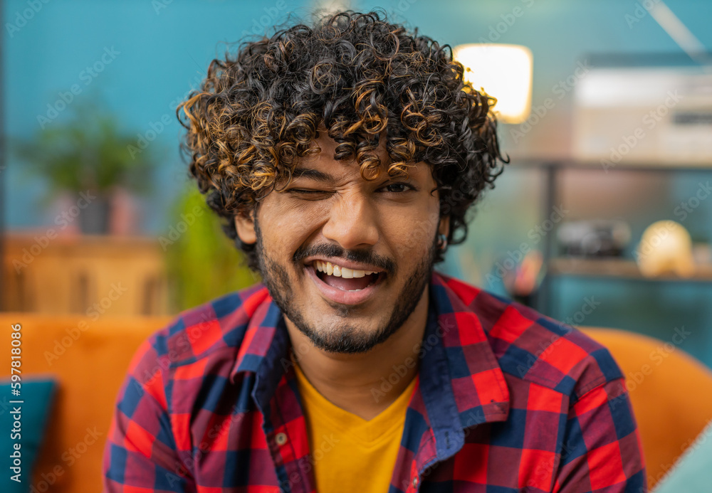 Smiling playful happy young indian man blinking eye, looking at camera ...