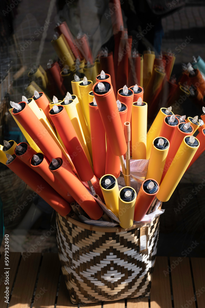 Red, orange and yellow torches with solar powered lights in a basket ...