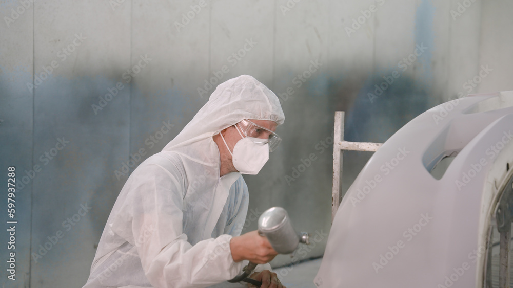 Caucasian car paint specialist in protective PPE suit Spraying air to ...