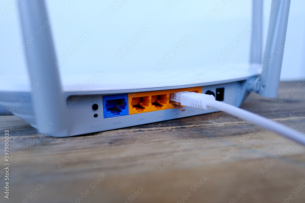 white cable is plugged into the port of Wi-Fi router, modern wireless ...