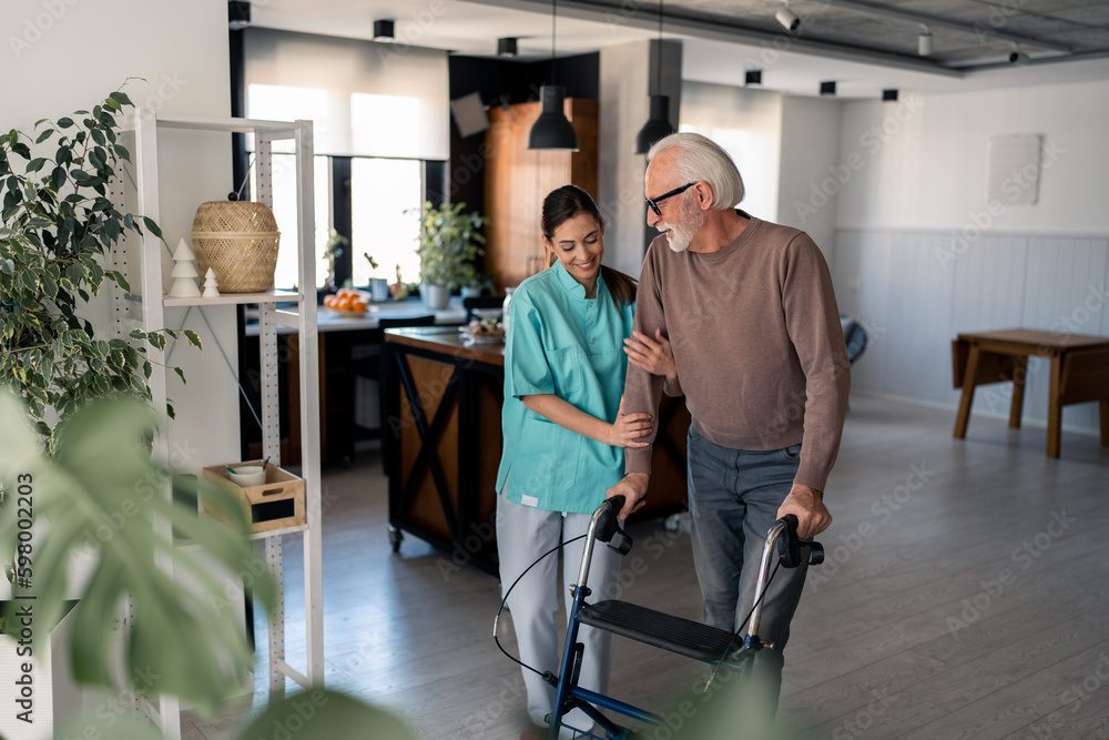 Caring physiotherapist assisting elderly male patient with glasses to ...