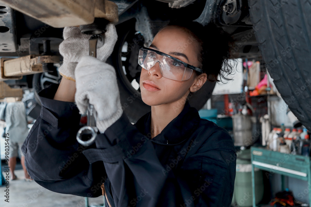 Beautiful female auto mechanic checking wheel tires in garage, car ...