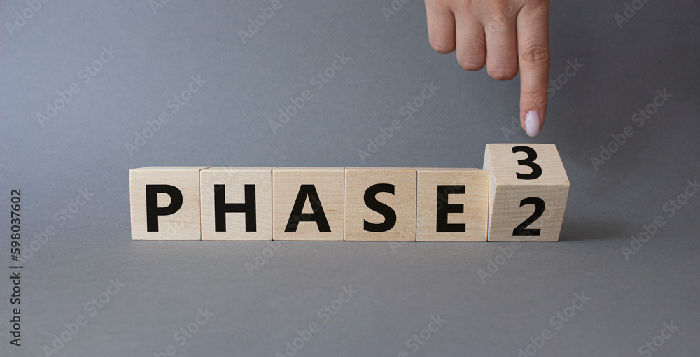 From Phase 2 to 3 symbol. Businessman Hand points at wooden cubes with ...
