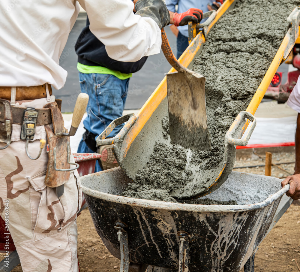 Wet cement off loaded by construction workers from a cement truck chute ...
