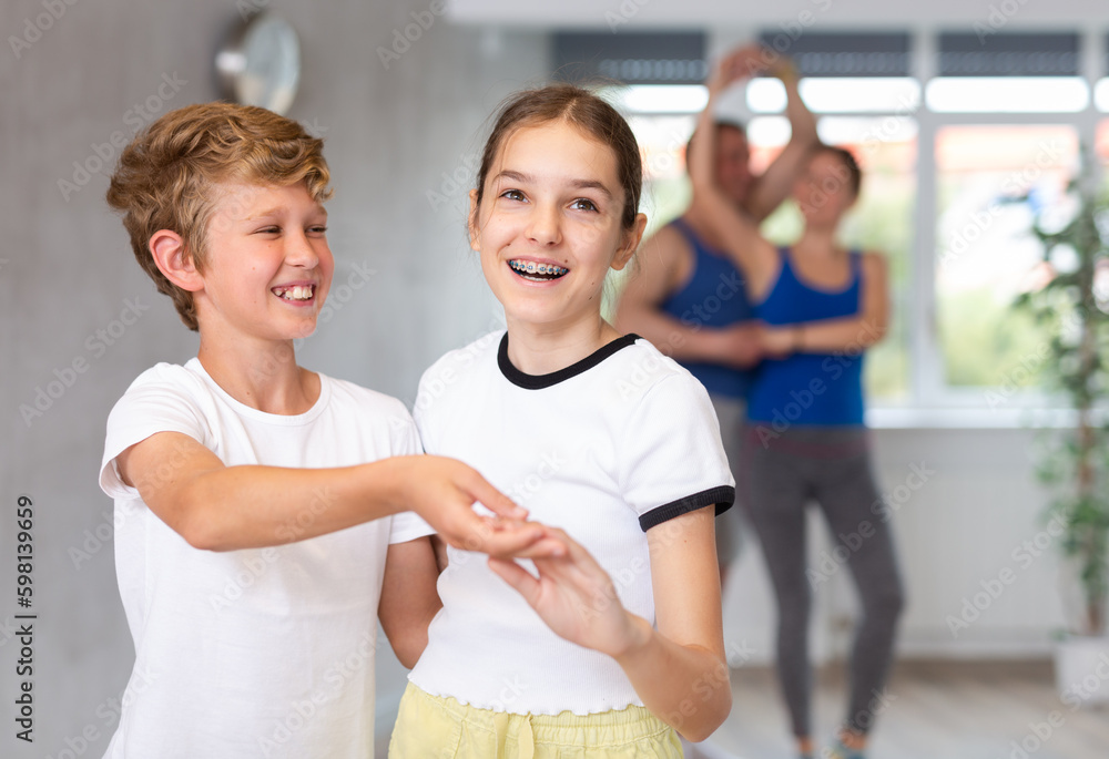 Cheerful friendly school children practicing active dance in pairs with ...