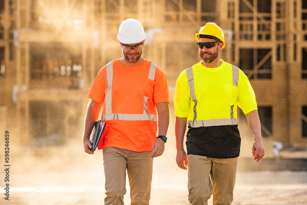 Two construction workers with hardhat helmet on construction site ...
