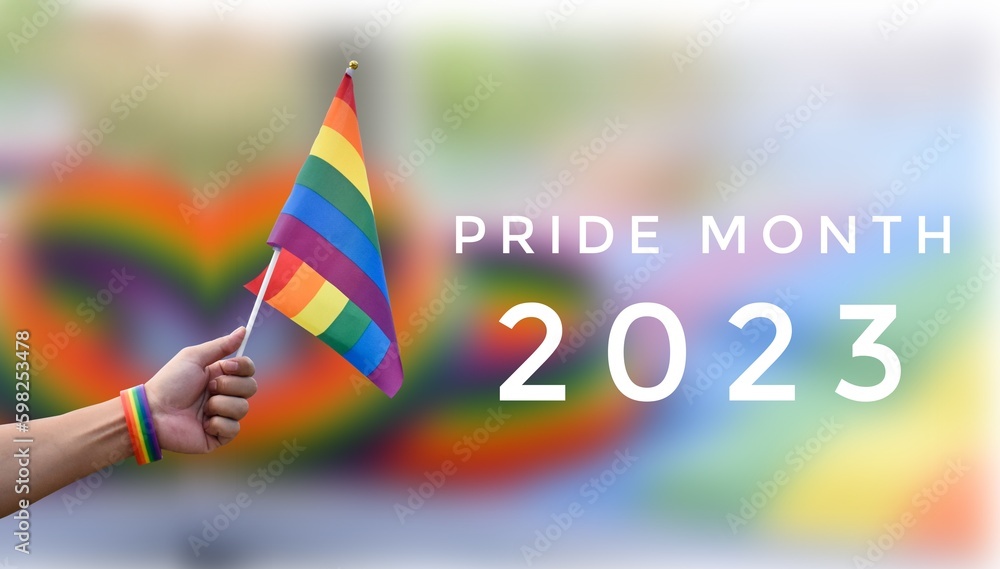 Pride Month 2023 On Blurred Rainbow Flag And Wristband Background