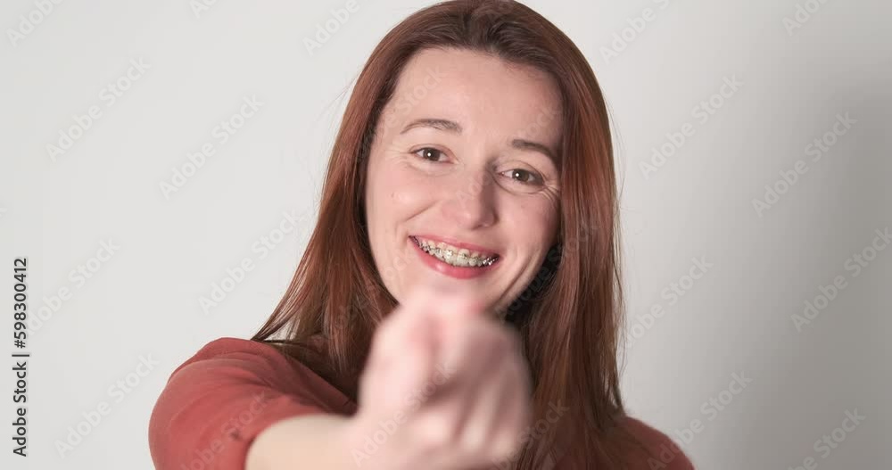 Woman beckon with finger, portrait, close-up. Female with braces teeth ...