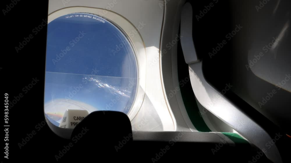 Emergency exit door handle in flying airplane with view of blue sky in ...