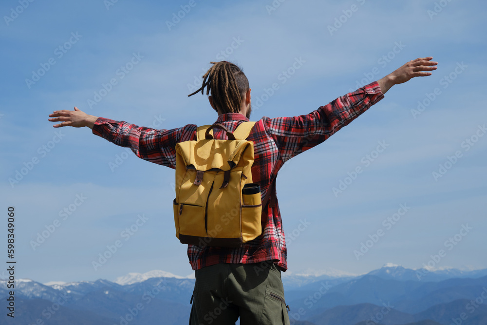 Young guy with dreadlocks went hiking in mountains. Man with yellow ...