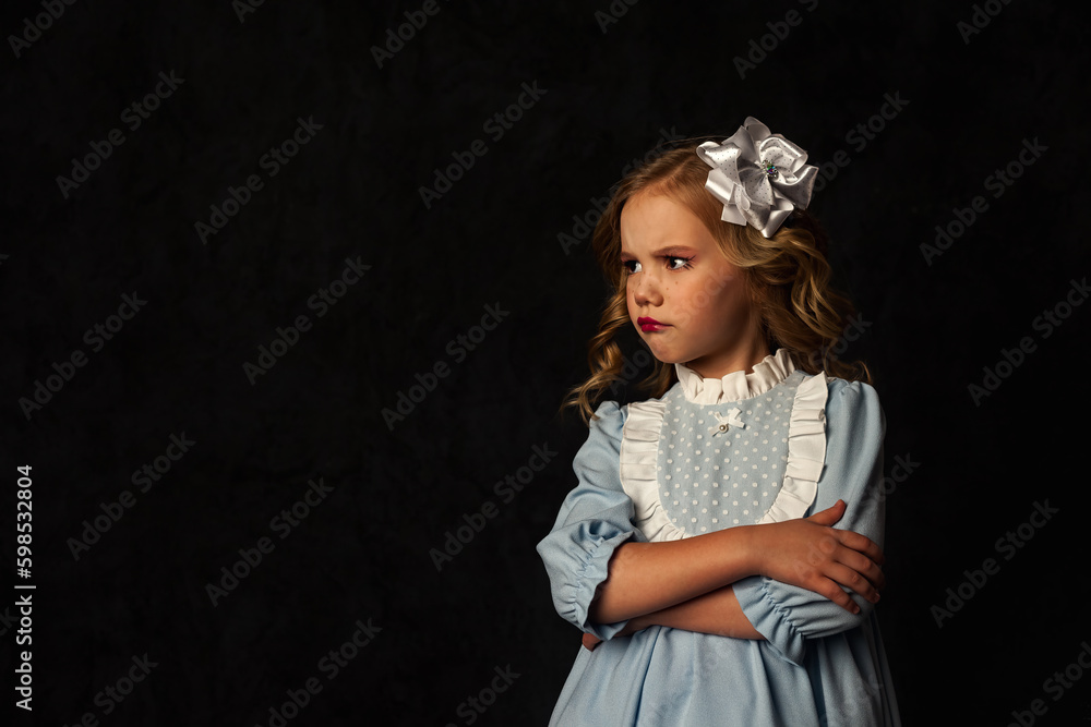 Frowning little doll cover girl in blue dress at black background ...