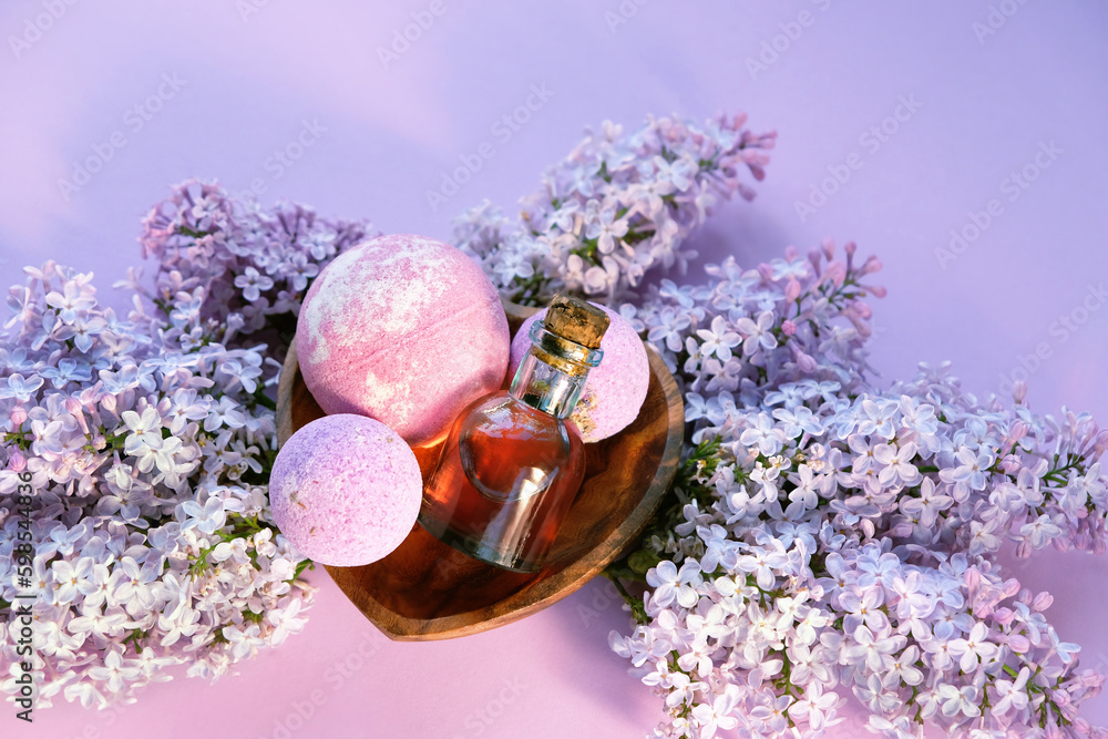 essential oil bottle, bath bombs and lilac flowers on abstract violet ...