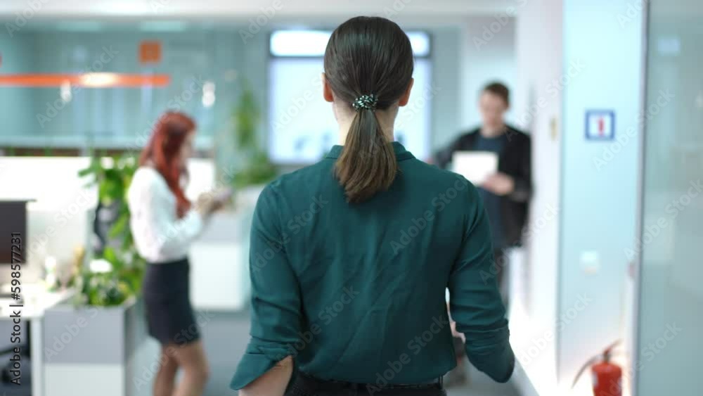 Tracking shot of confident young woman walking in office greeting ...