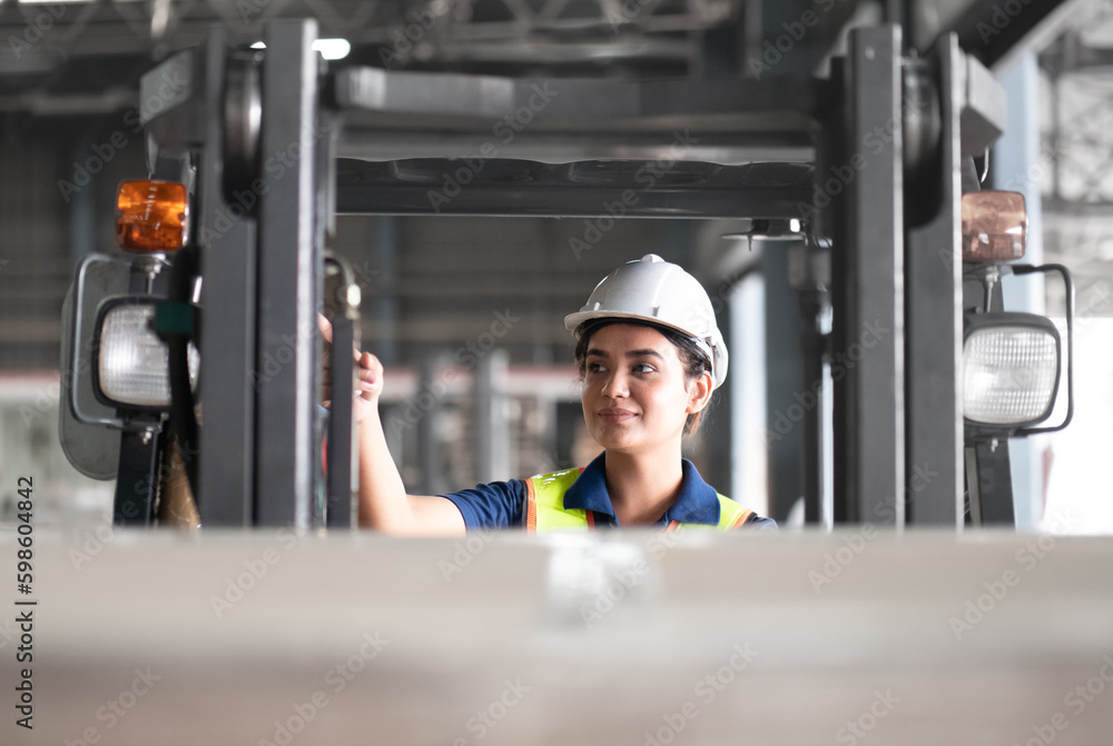 Professional female industrial driver operating forklift truck in ...