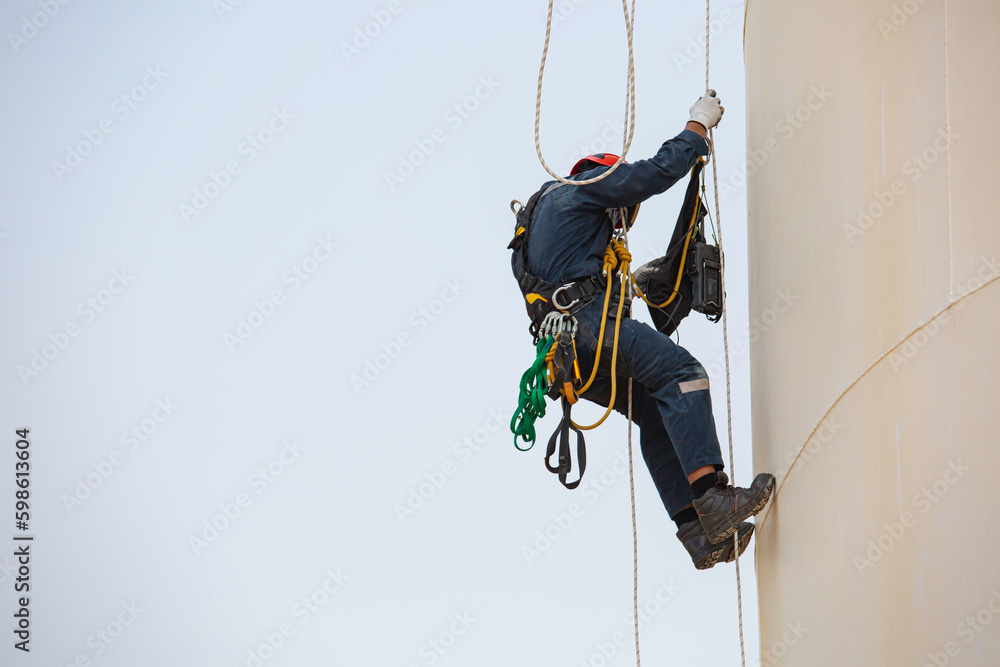 Male worker rope access industrial working at height tank oil wearing ...