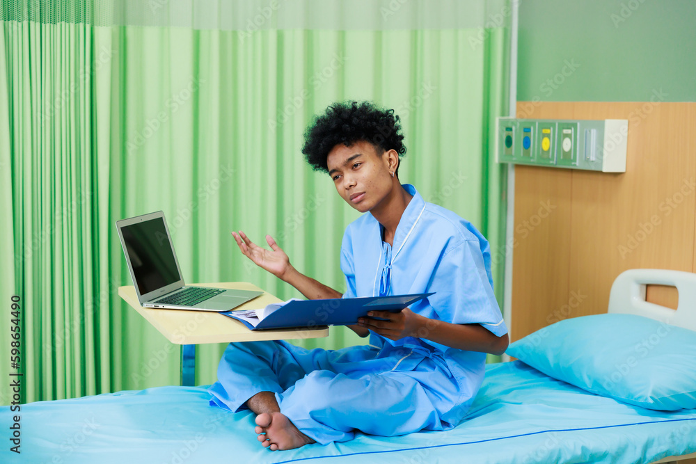 Black male patient working on laptop computer on hospital bed at ...