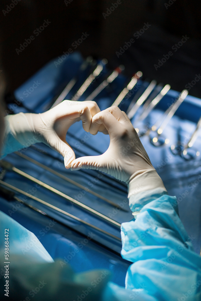 the doctor shows the heart sign with his hands after the operation on ...