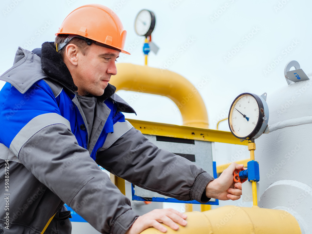 Foto de Caucasian worker at gas distribution station opens valve on gas ...