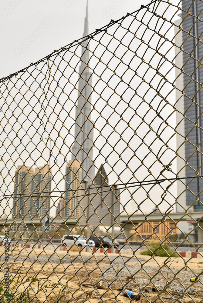 Blurred the iconic skyscraper Burj khalifa behind the fence. Dubai, UAE ...