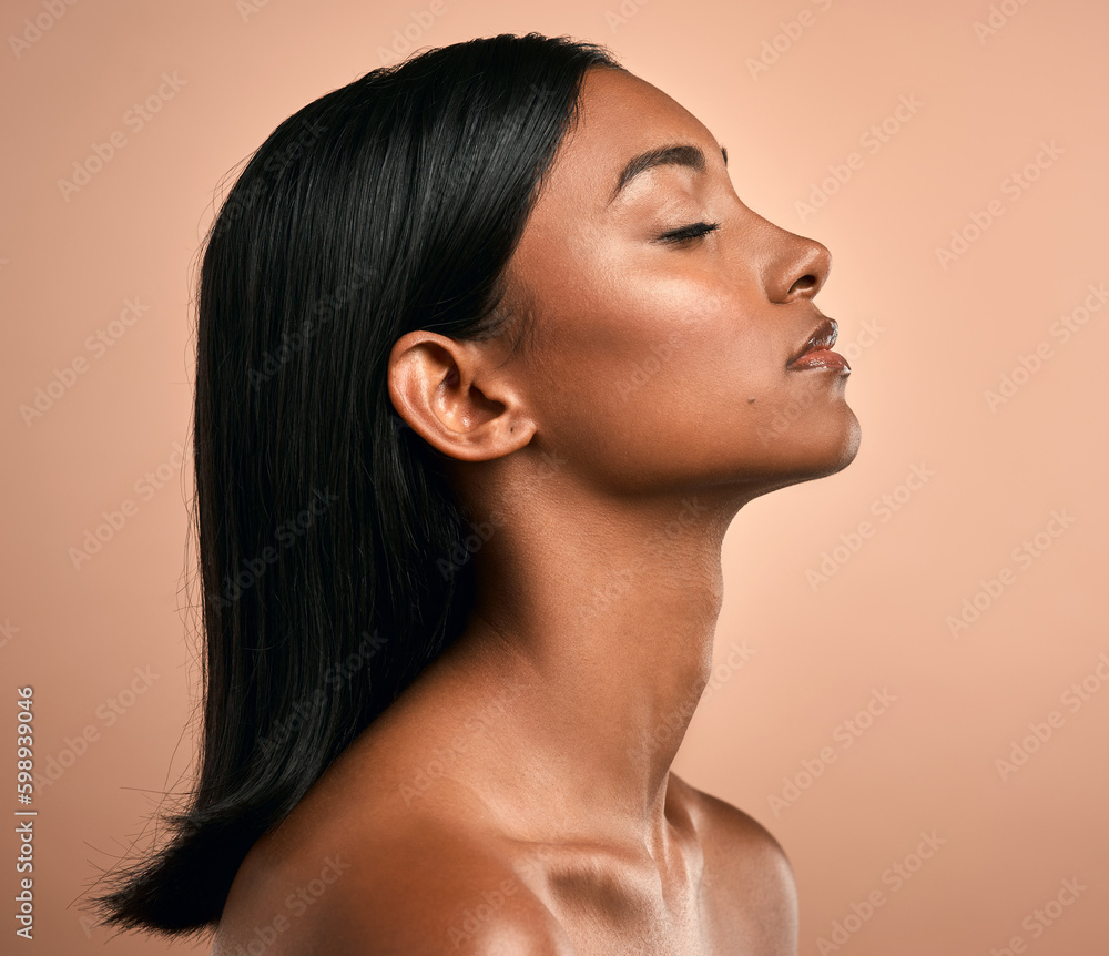 Love yours. Side shot of a beautiful young woman posing against a brown ...