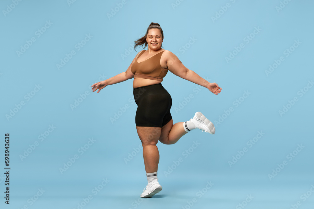 Young, happy, active, overweight woman training in sportswear against ...