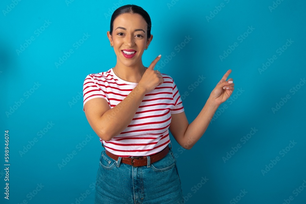 Positive beautiful woman wearing striped T-shirt over blue studio ...
