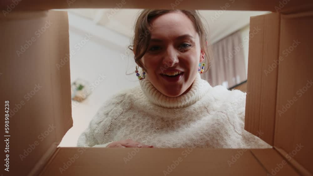 Inside view from box. Young happy woman unpacking delivery parcel at ...