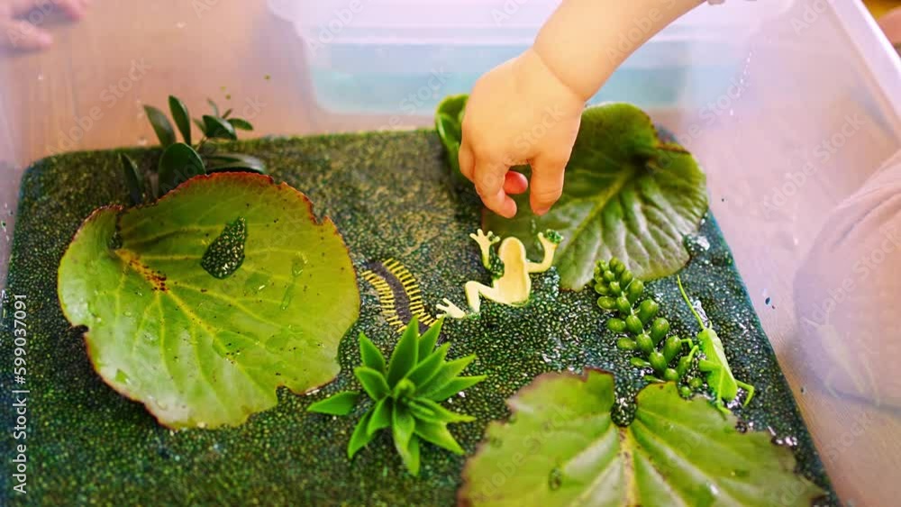 Little girl playing in handmade swamp of green-dyed chia seeds with ...