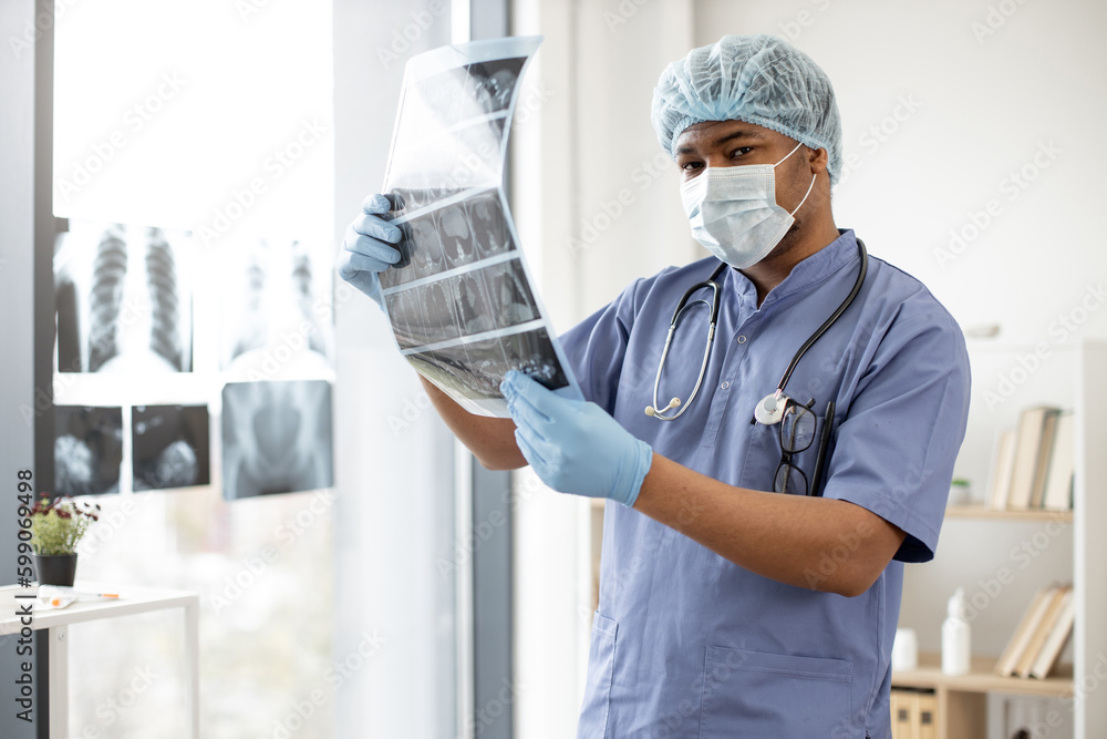 Mindful multiethnic man in protective garment holding detailed CT scan ...