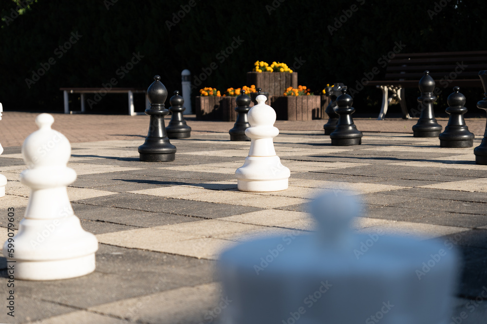 Outdoor chess board with big plastic pieces. Giant chess in public area ...