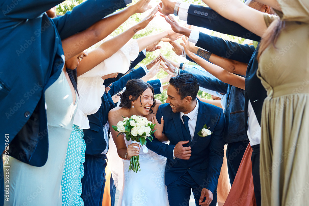 Wedding guests forming a tunnel with their hands as newlywed couple ...