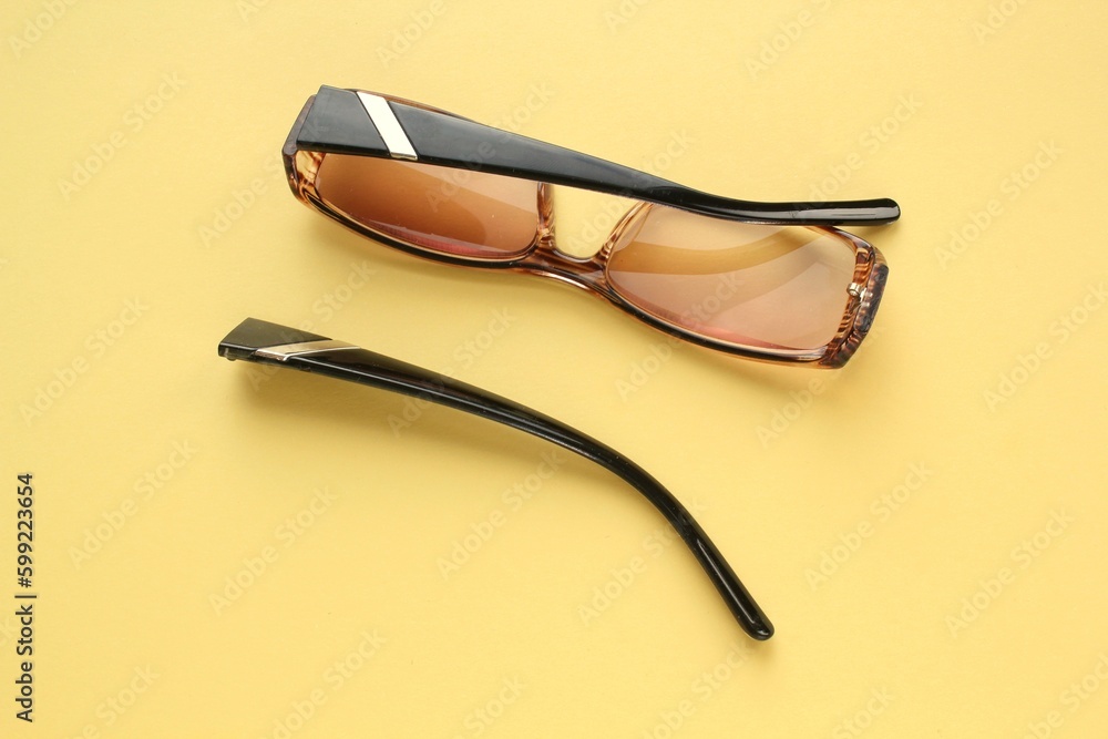 Old broken eyeglasses with damaged legs on orange background. Poor ...
