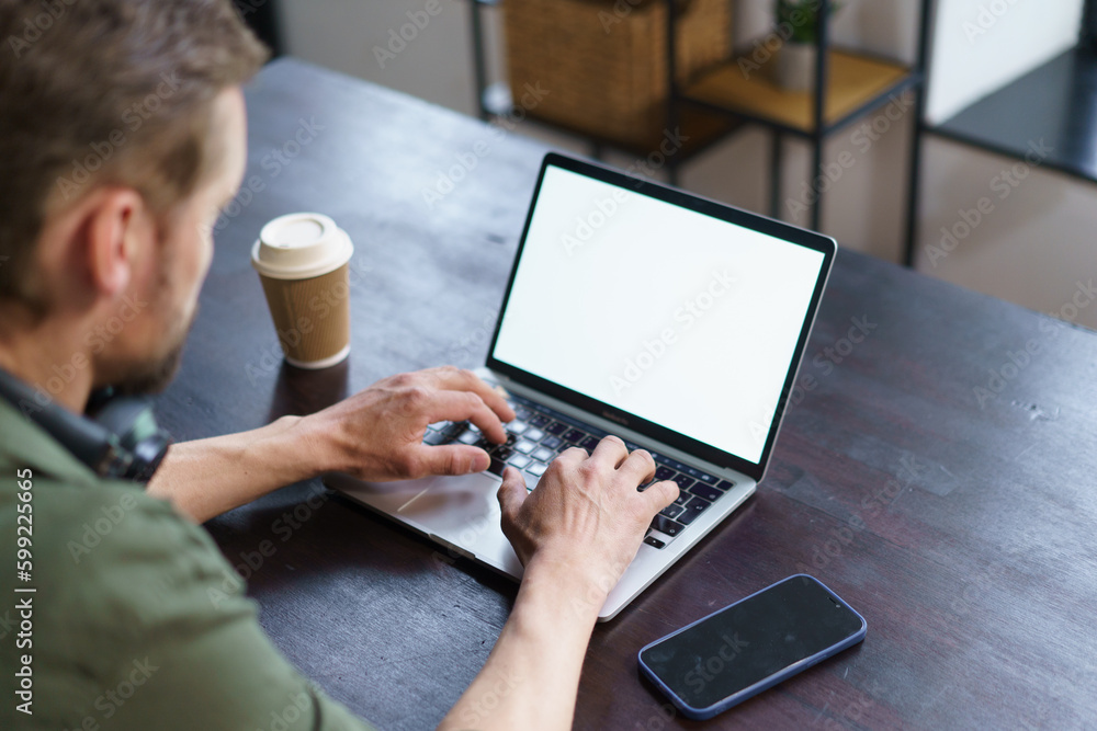 man working on laptop in loft office. man seated at desk with laptop ...
